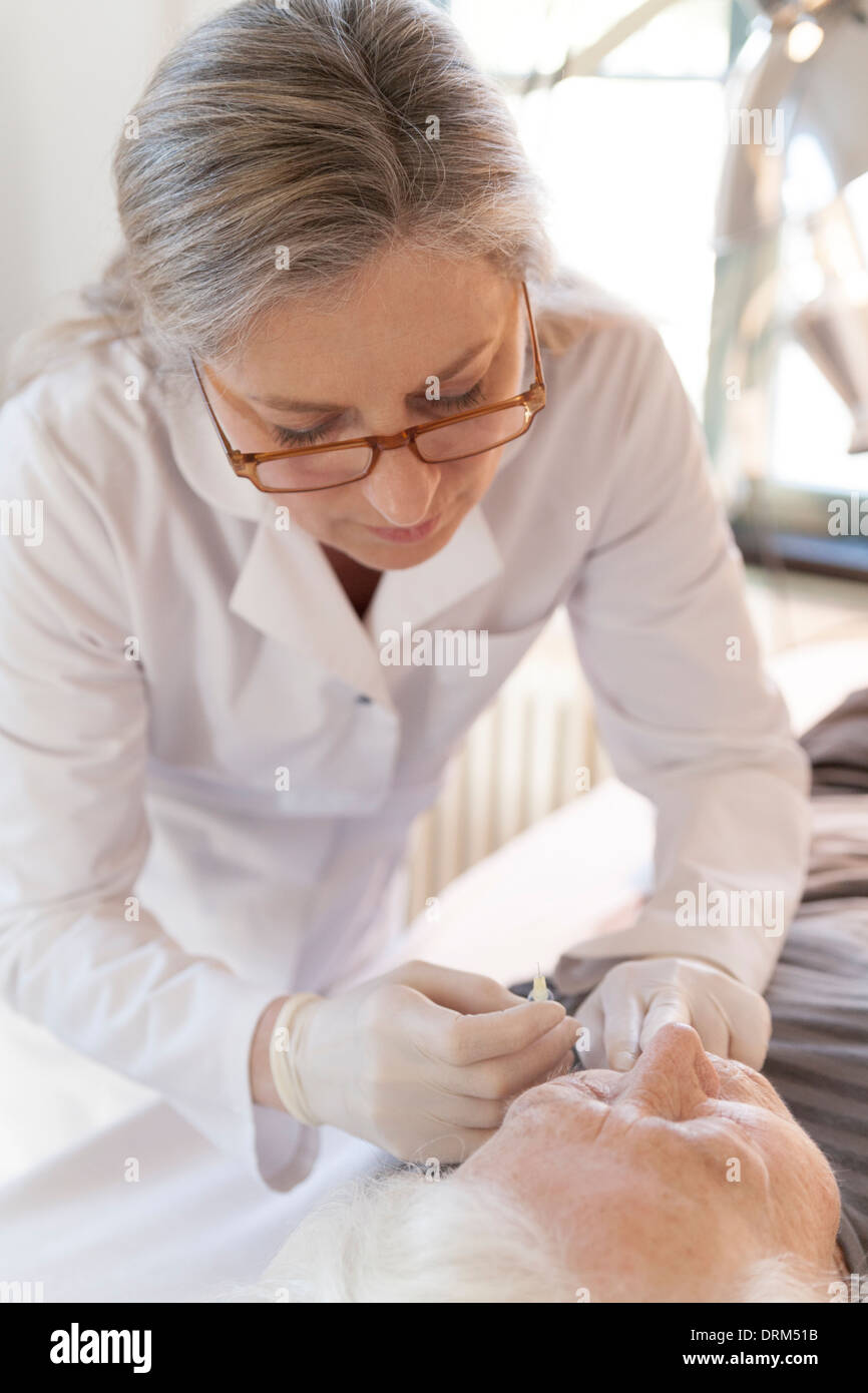 Female alternative practitioner giving senior woman injection ...