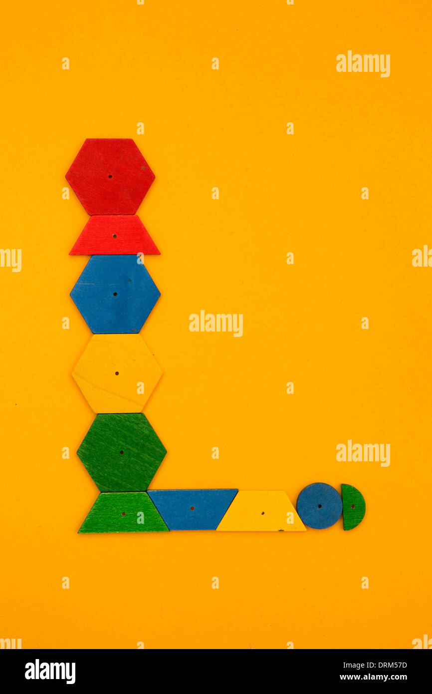 Letter "L" formed of colored geometric wooden forms at yellow ...