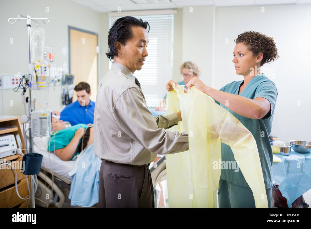 Nurse Assisting Doctor In Wearing Operation Gown At Hospital Stock ...