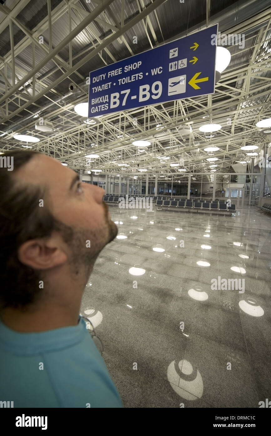 Young man looking direction billboard in airport Stock Photo - Alamy