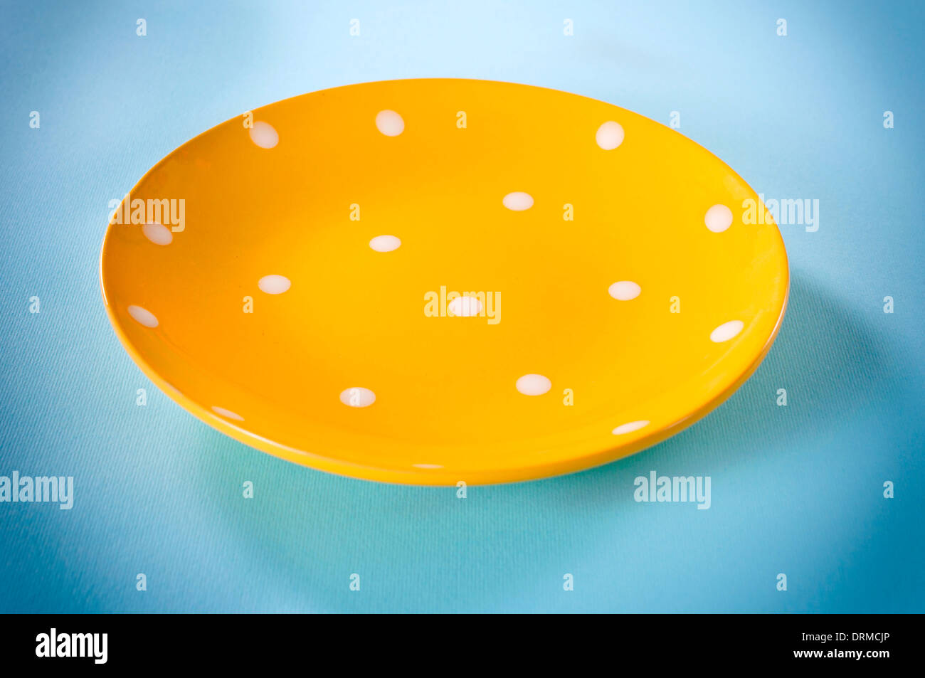 Empty yellow plate on the light blue background Stock Photo - Alamy