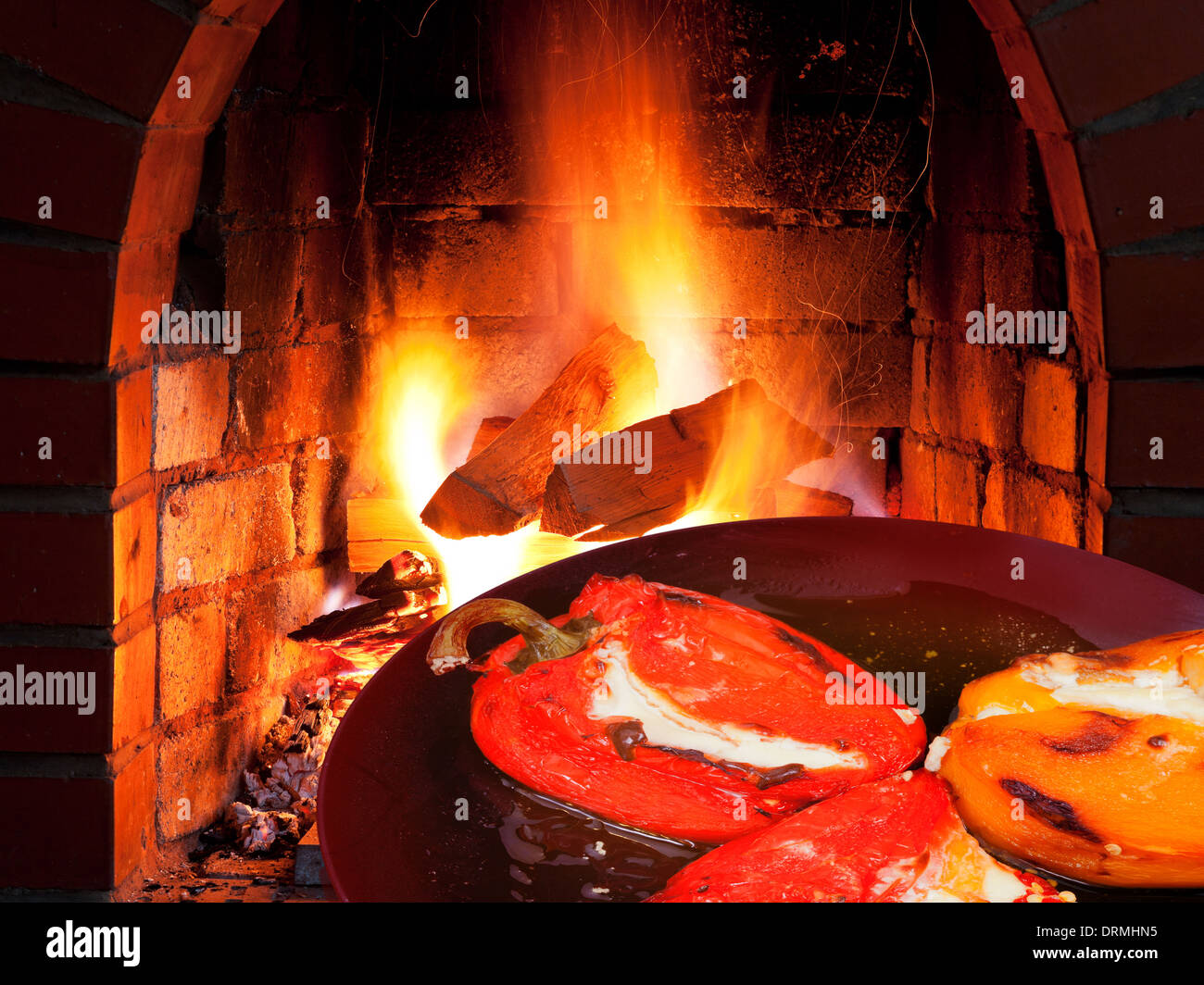 plate of roasted pepper with goat cheese and fire in wood burning oven ...
