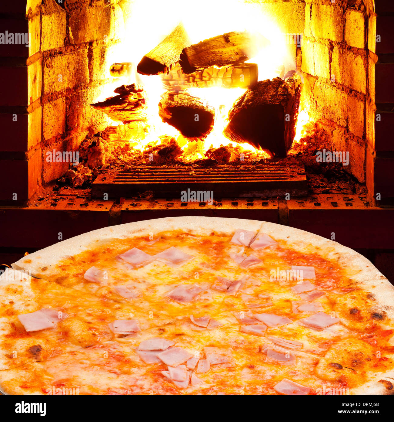 italian pizza with prosciutto cotto and open fire in wood burning stove ...