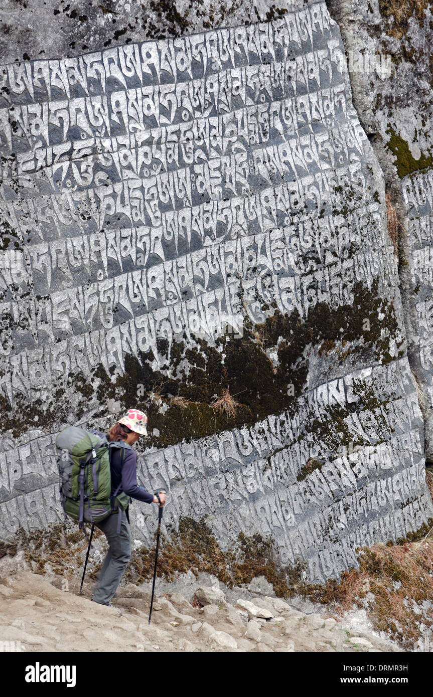 A lady trekker descending steps by a huge mani wall on the everest base ...