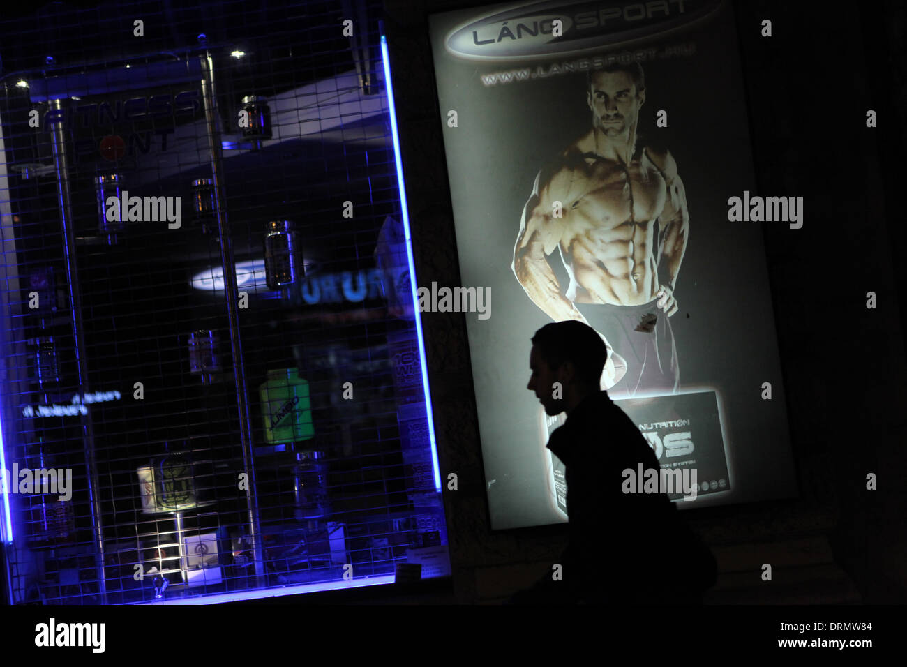 A man passes a shop window decorated with advertisement of bodybuilding ...