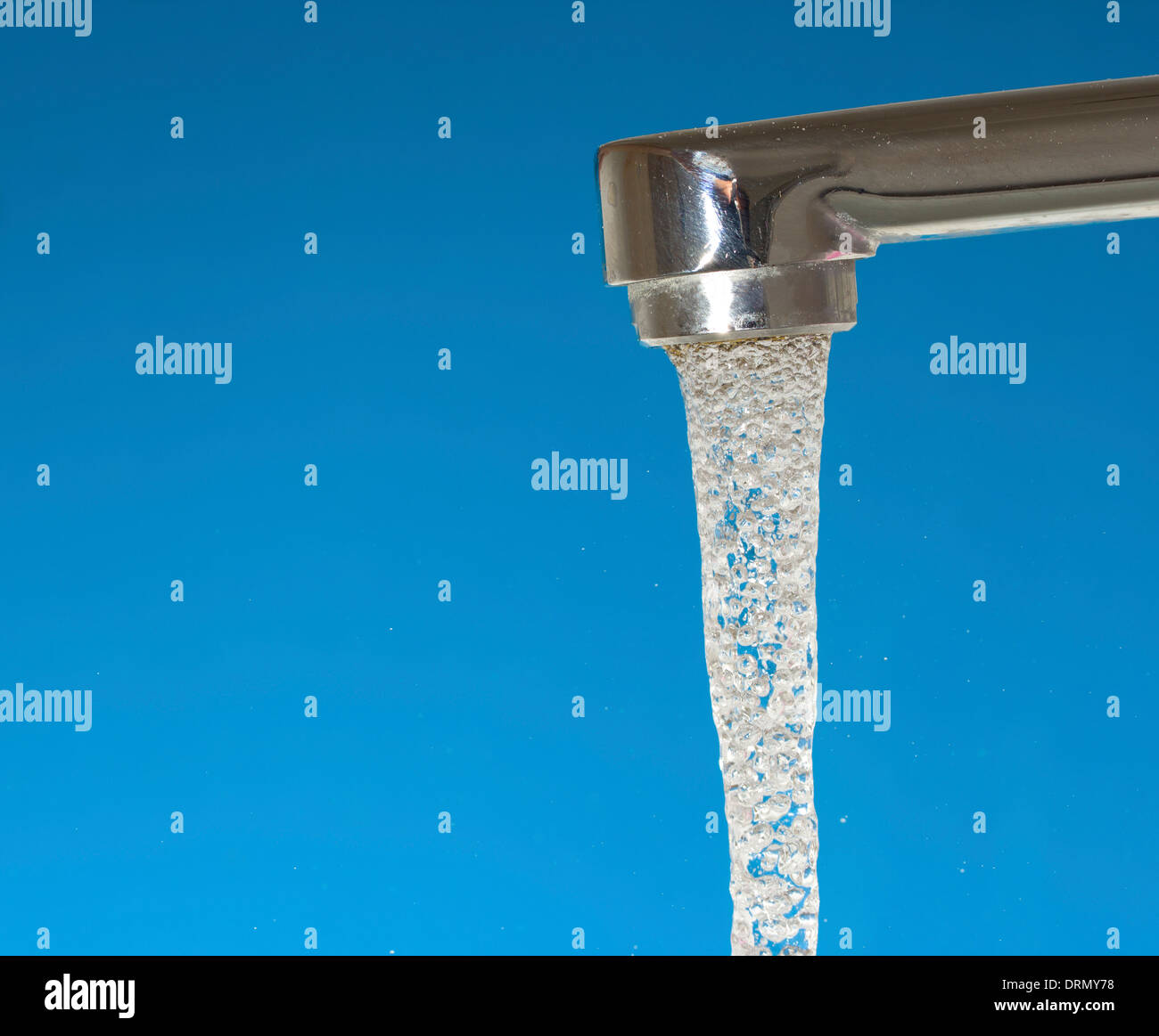 Water flowing from a tap on the blue background Stock Photo - Alamy