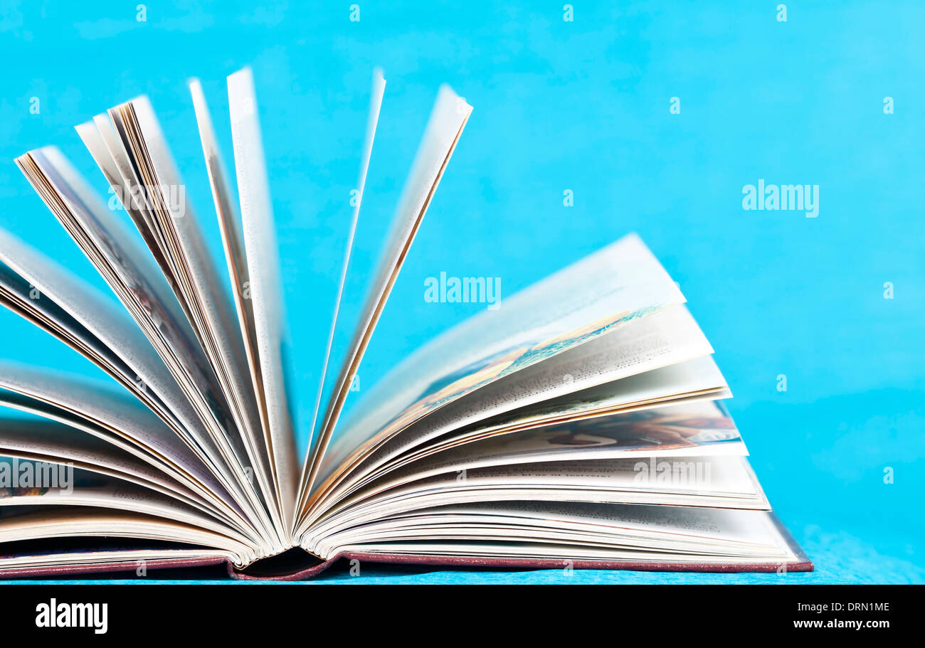 Open book in front of blue background Stock Photo - Alamy