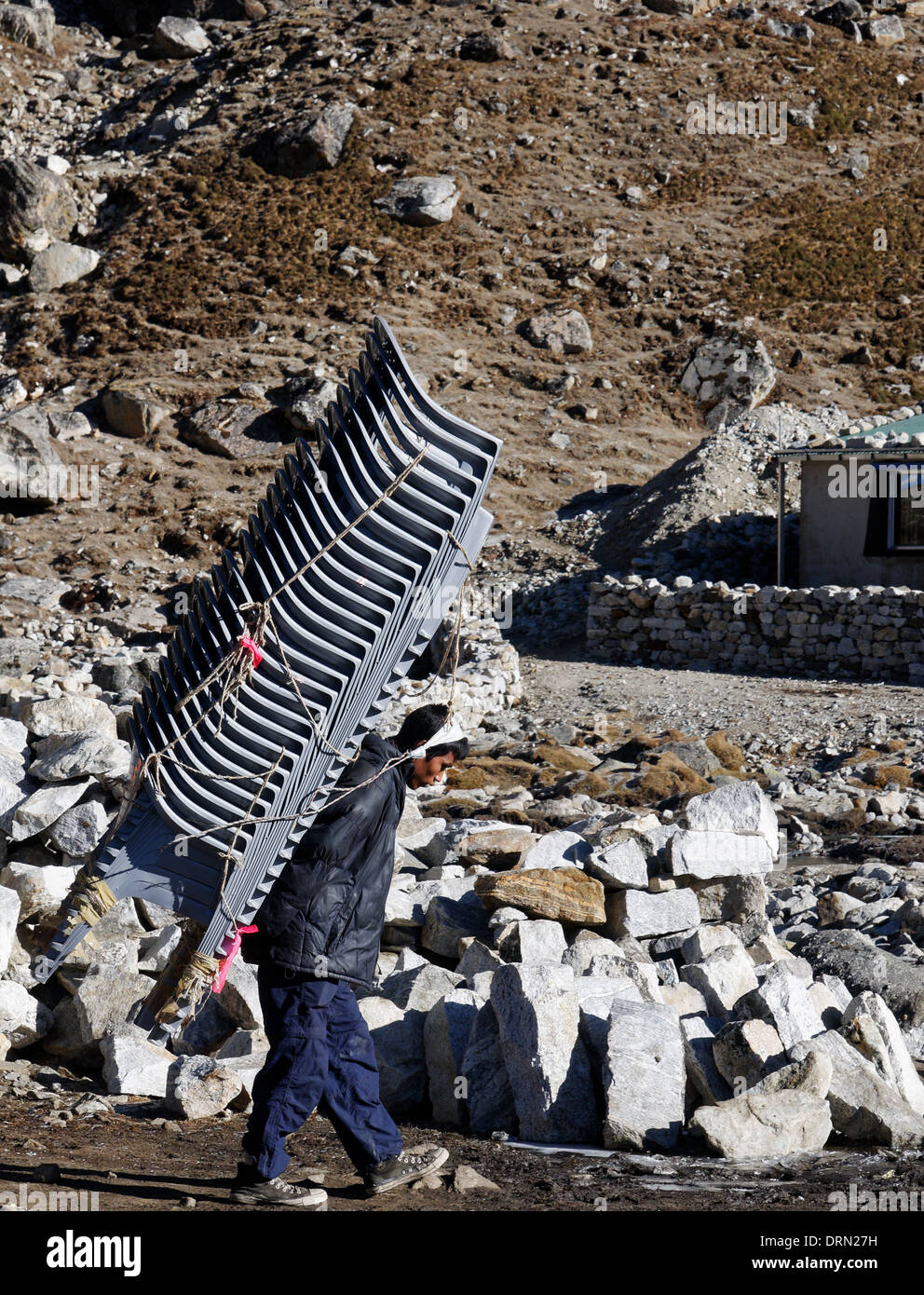 A nepali porter carrying a huge load of plastic chairs Stock Photo - Alamy