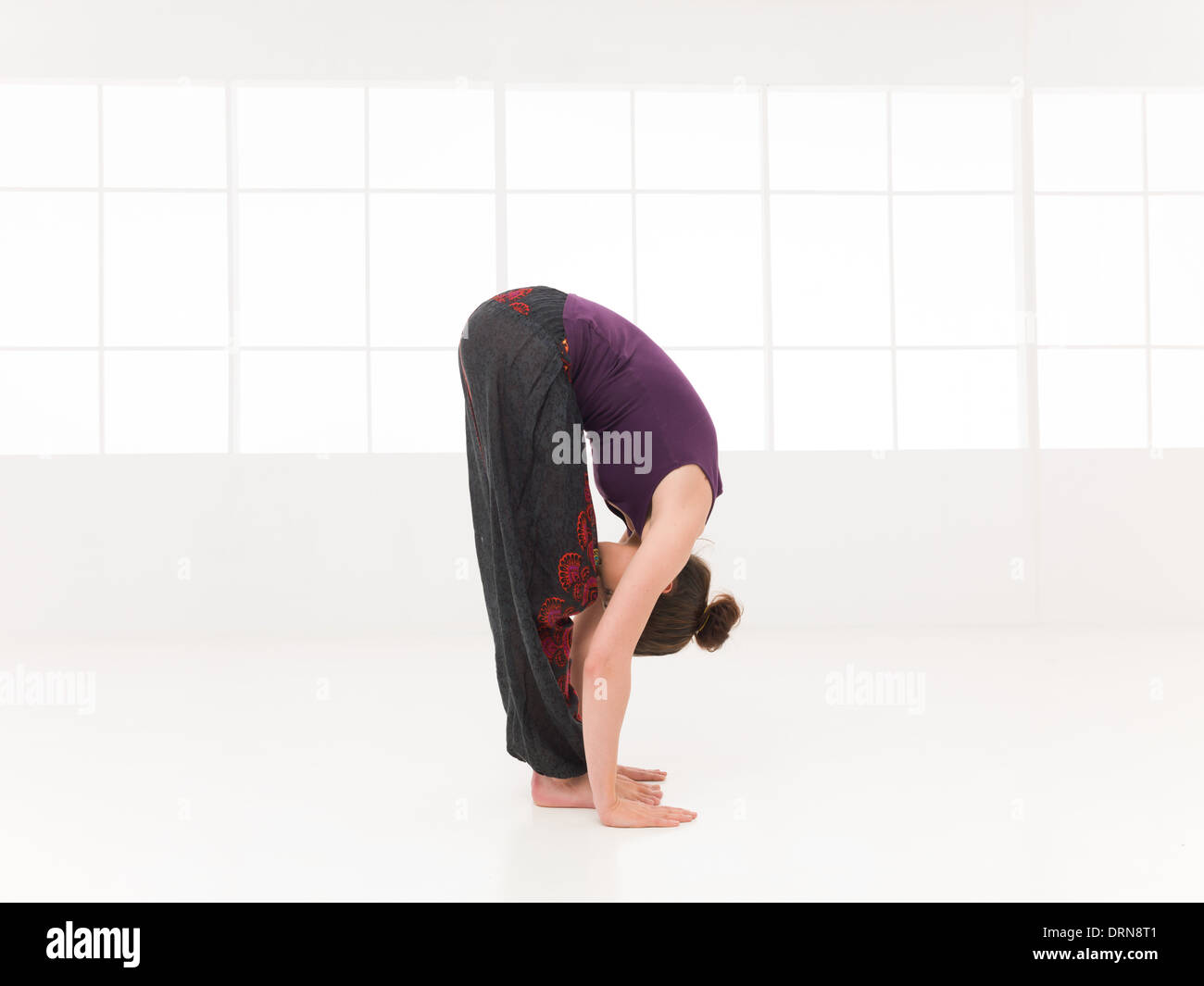 forward bending yoga pose, shown by younf female, dreesed colorful, on ...