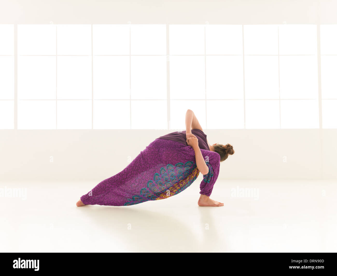 back view of adavnced balancing yoga posture, demonstrated by young ...