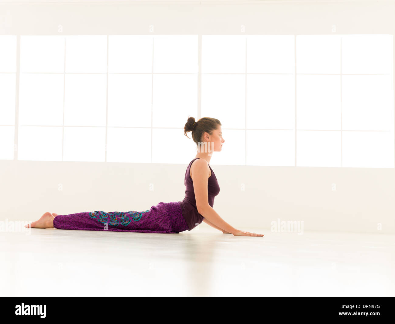 young woman demonstrating difficult yoga posture, full body side view ...