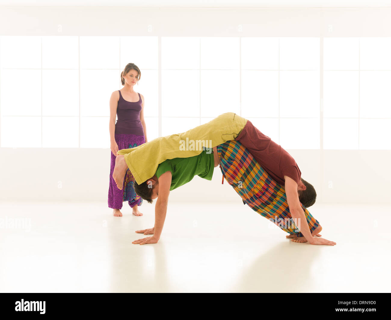 Three young people a woman and two men practice yoga partner in class ...