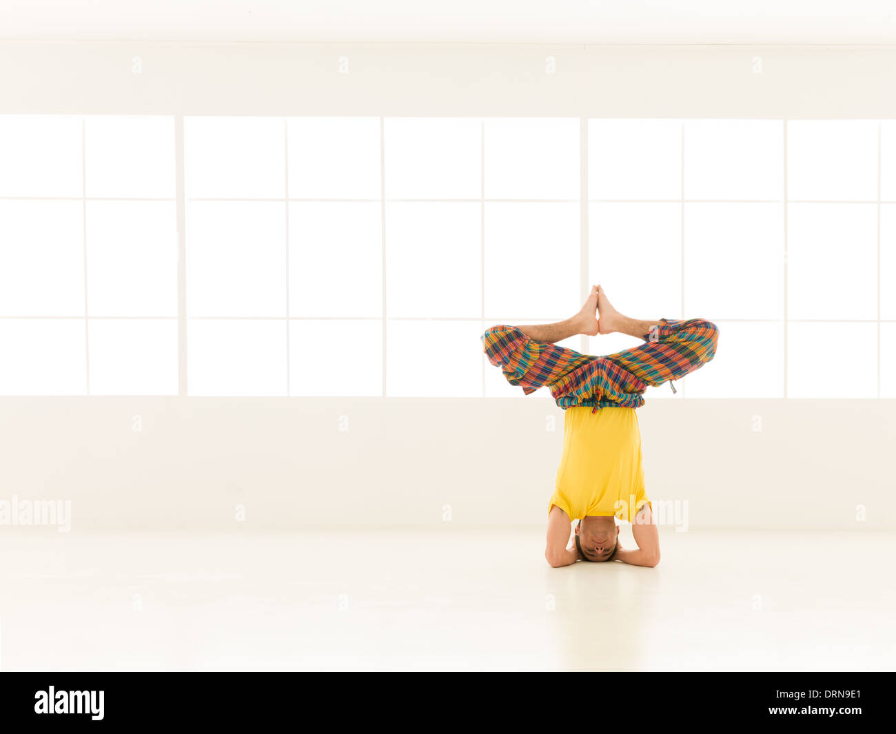 close up of single young man in advanced yoga posture, dressed colorful ...