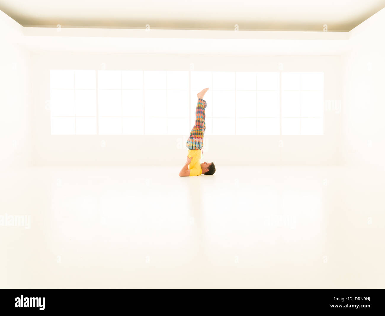 young repeating Sarvangasana Yoga exercises in a white room with window ...