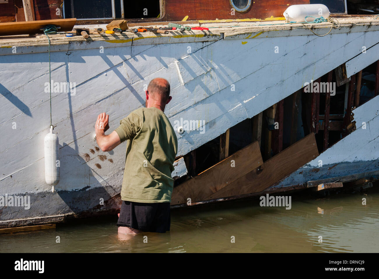 Man repairing hole in boat Stock Photo - Alamy