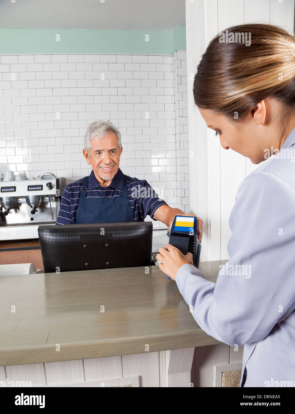 Woman Making Payment Through Mobilephone At Counter Stock Photo - Alamy