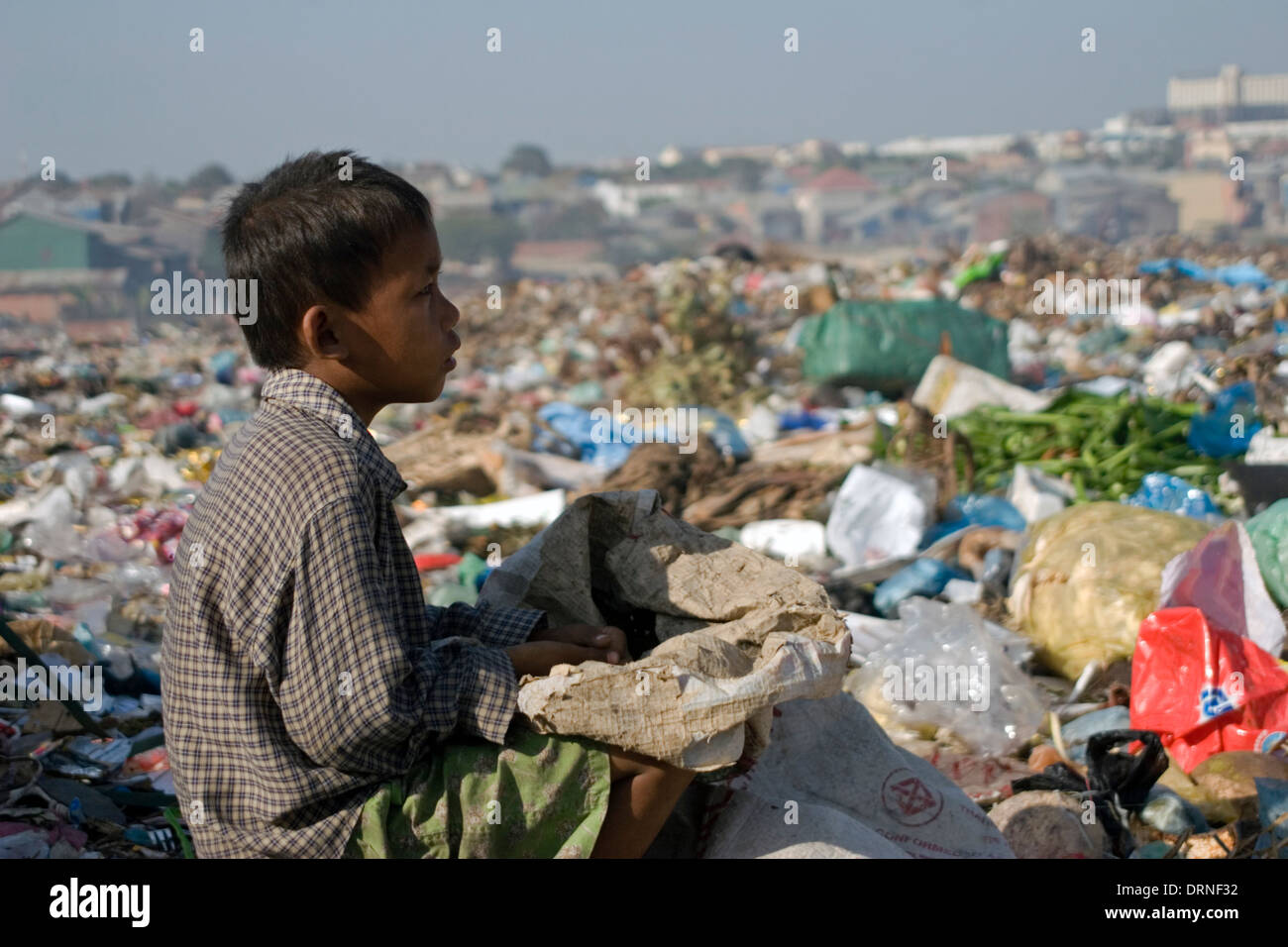 A young boy working as a scavenger is sitting in the toxic and polluted ...