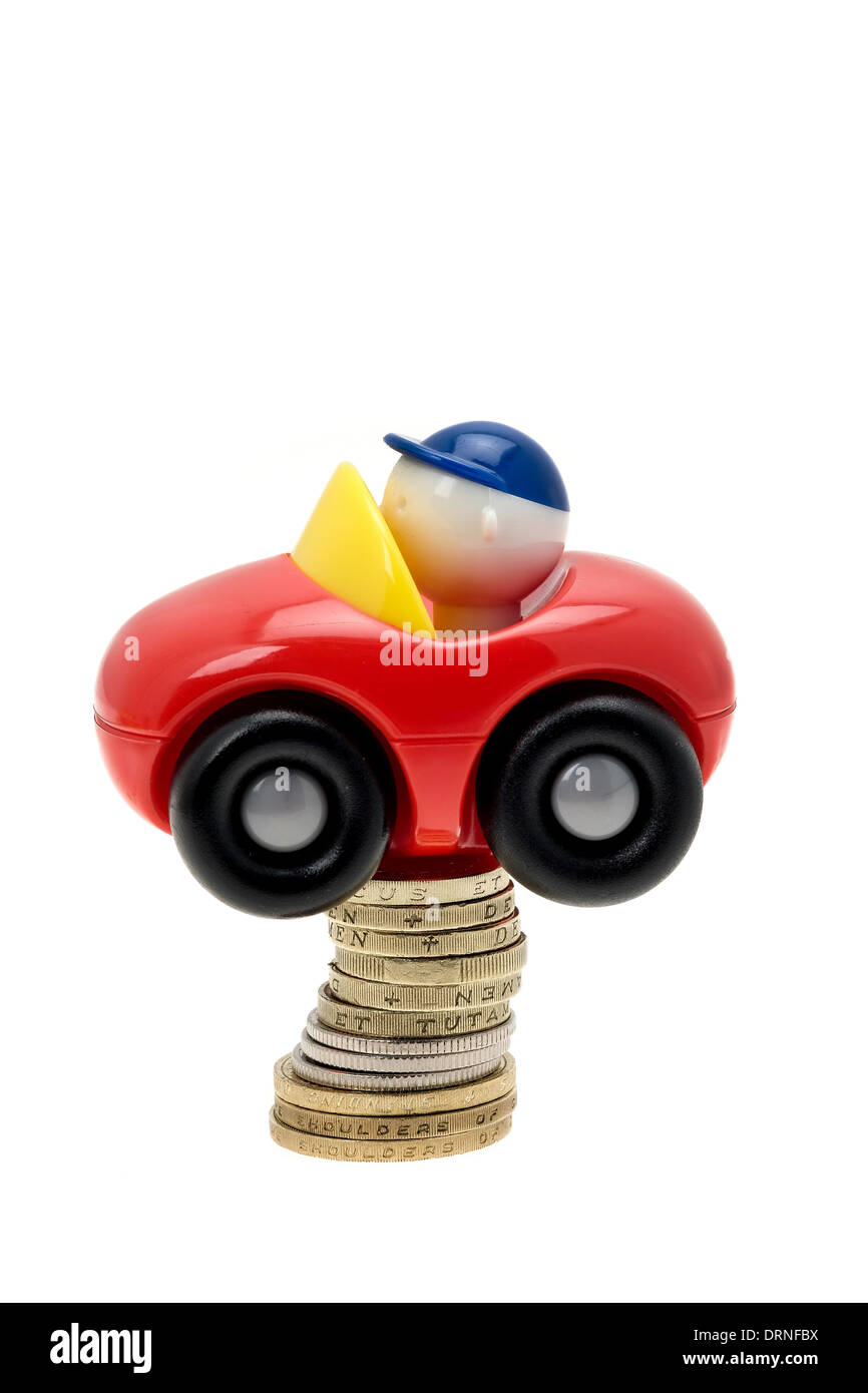 A red toy car placed on top of a pile of coins - studio shot with a ...