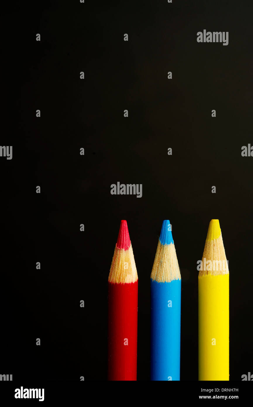 Children's red, blue and yellow coloured pencil crayons on a black ...