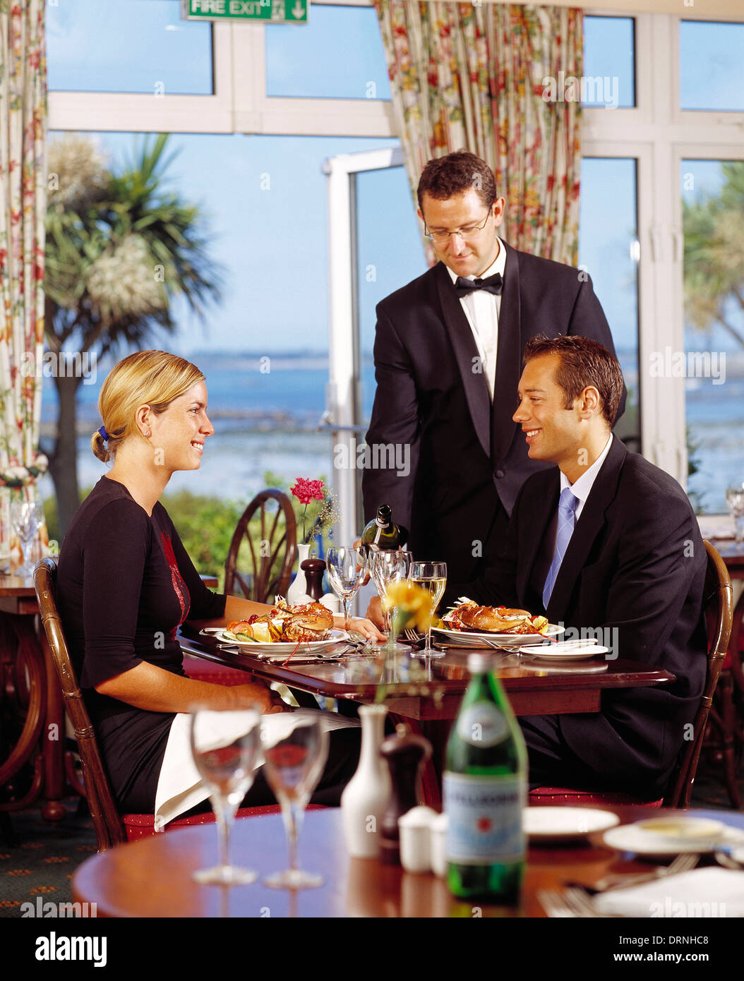 Waiter serving couple dining at hotel. British Channel Islands ...