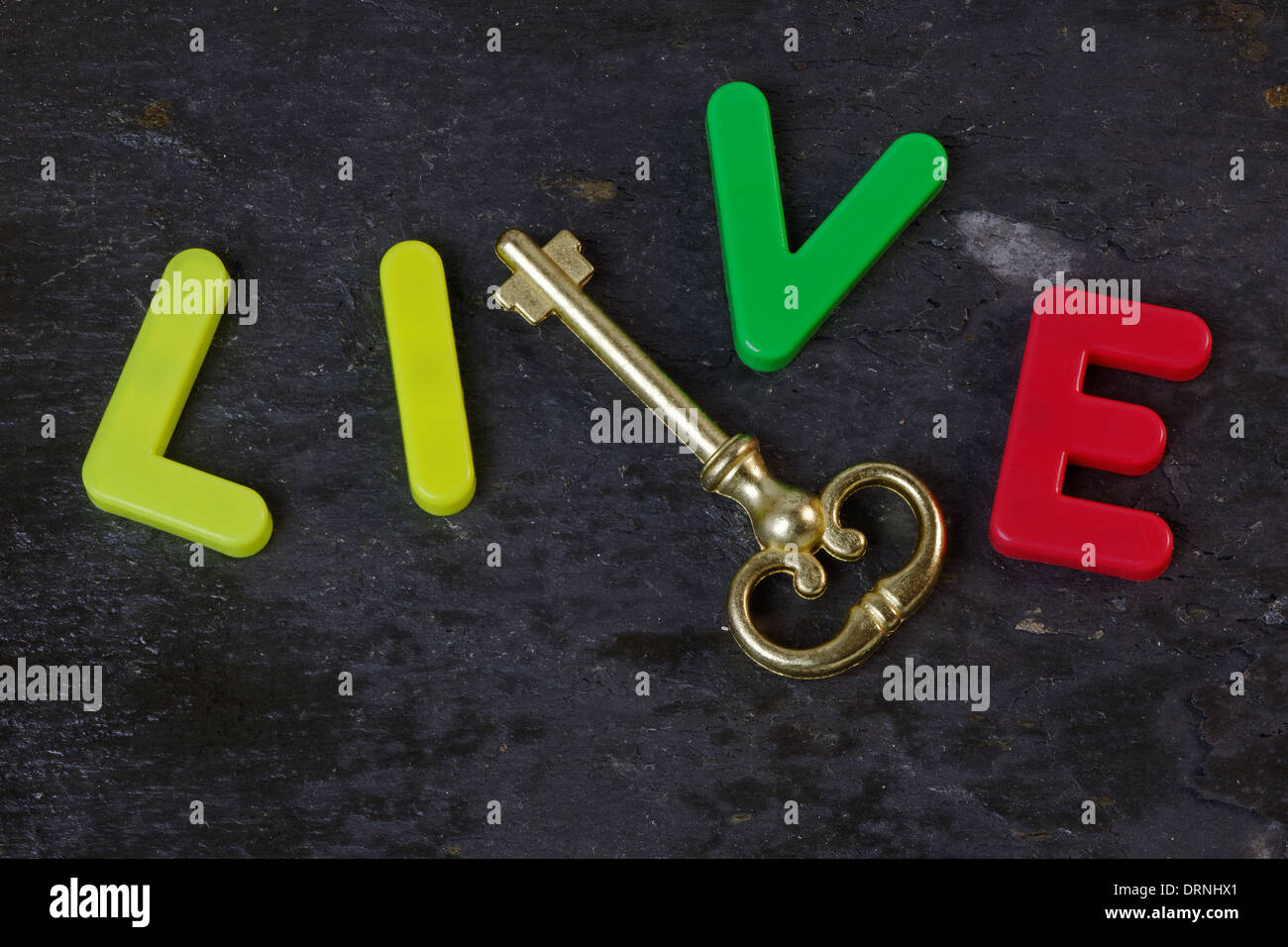 Antique key on a slate background with the word live in letters Stock ...