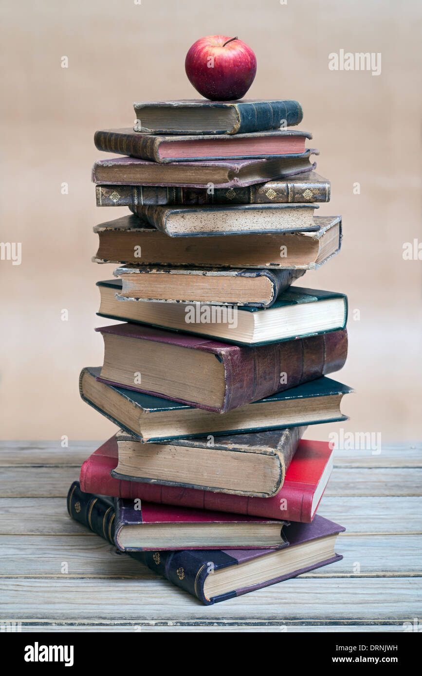 Apple on a pile of old books stacked Stock Photo - Alamy