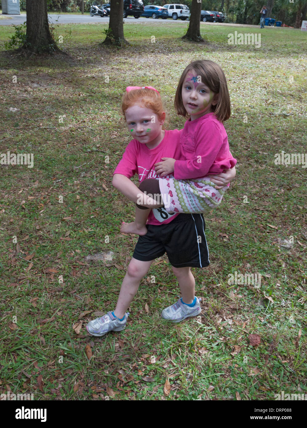 Girl carrying her friend across the grass Stock Photo - Alamy