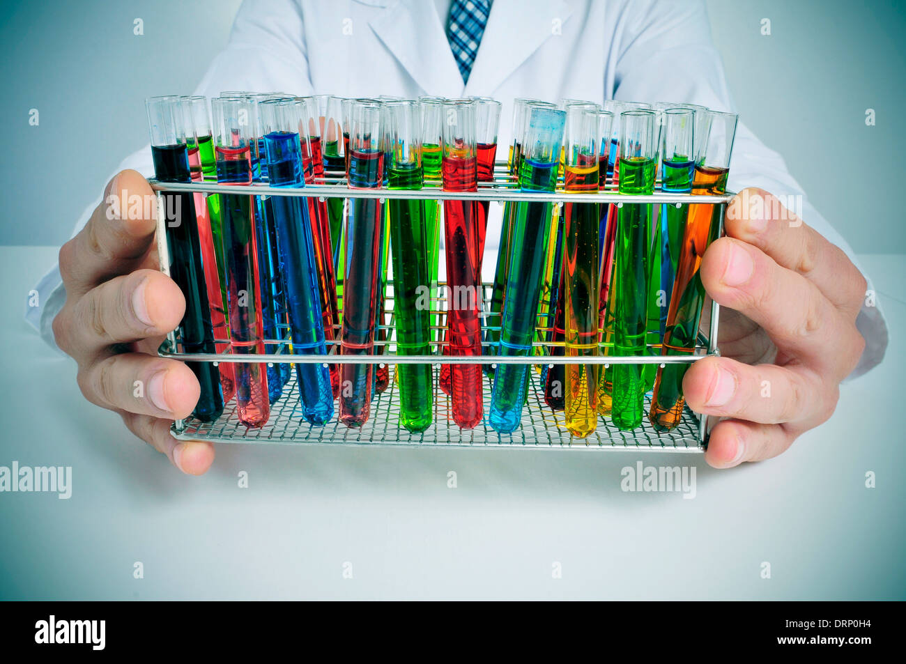 man in white coat with test tubes with liquids of different colors in a ...