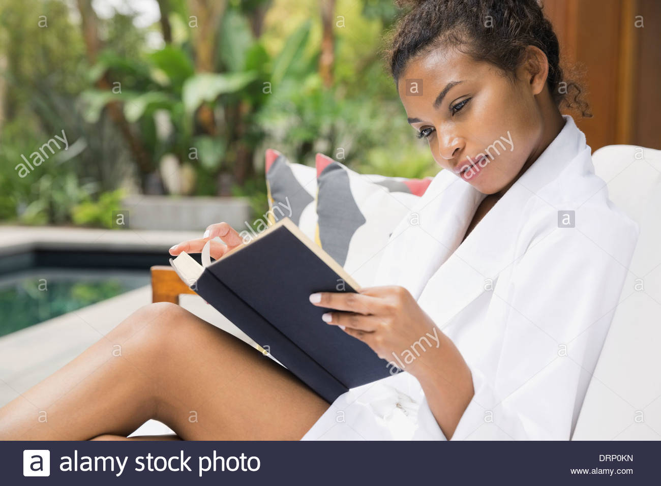 Woman reading book by pool hi-res stock photography and images - Alamy