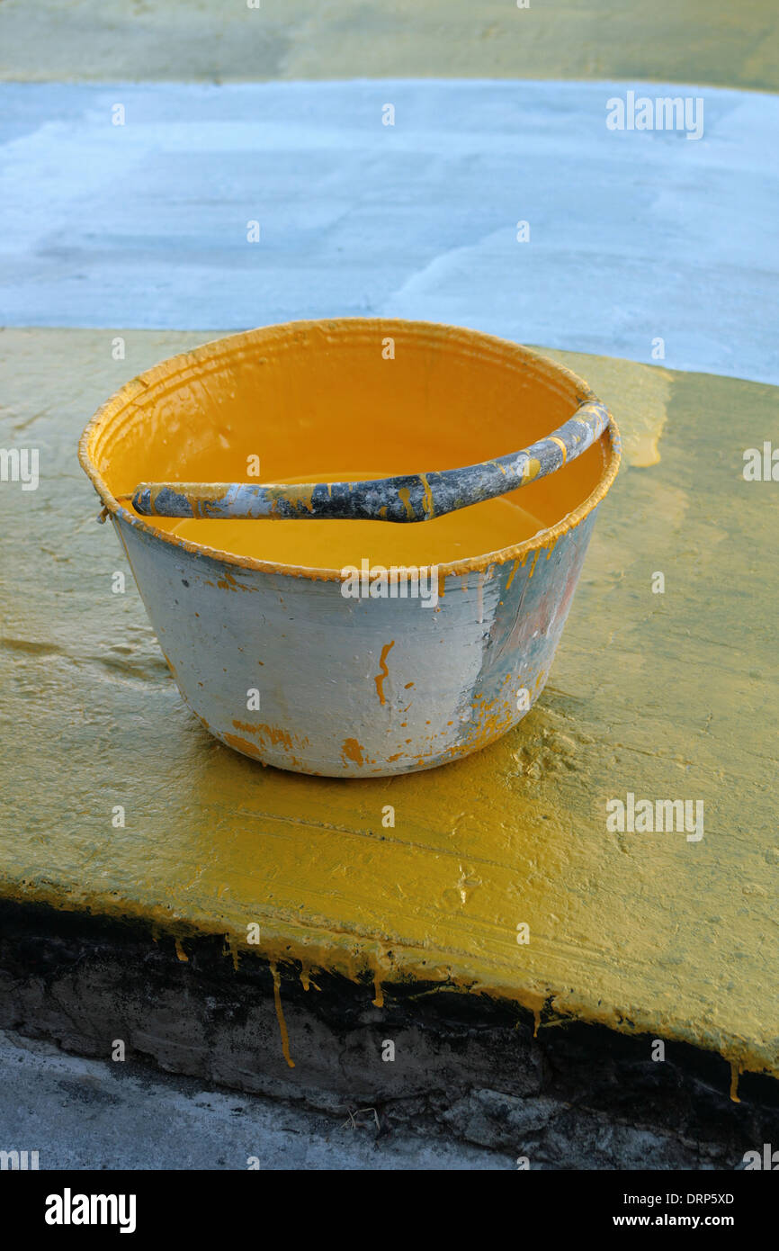 A steel bucket filled with yellow road paint at a road construction ...