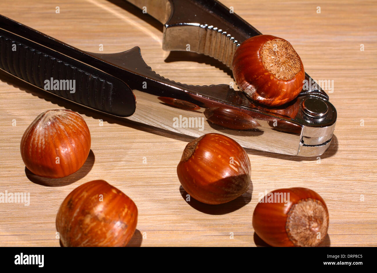 Hazelnuts and nut cracker on a wood effect background Stock Photo - Alamy