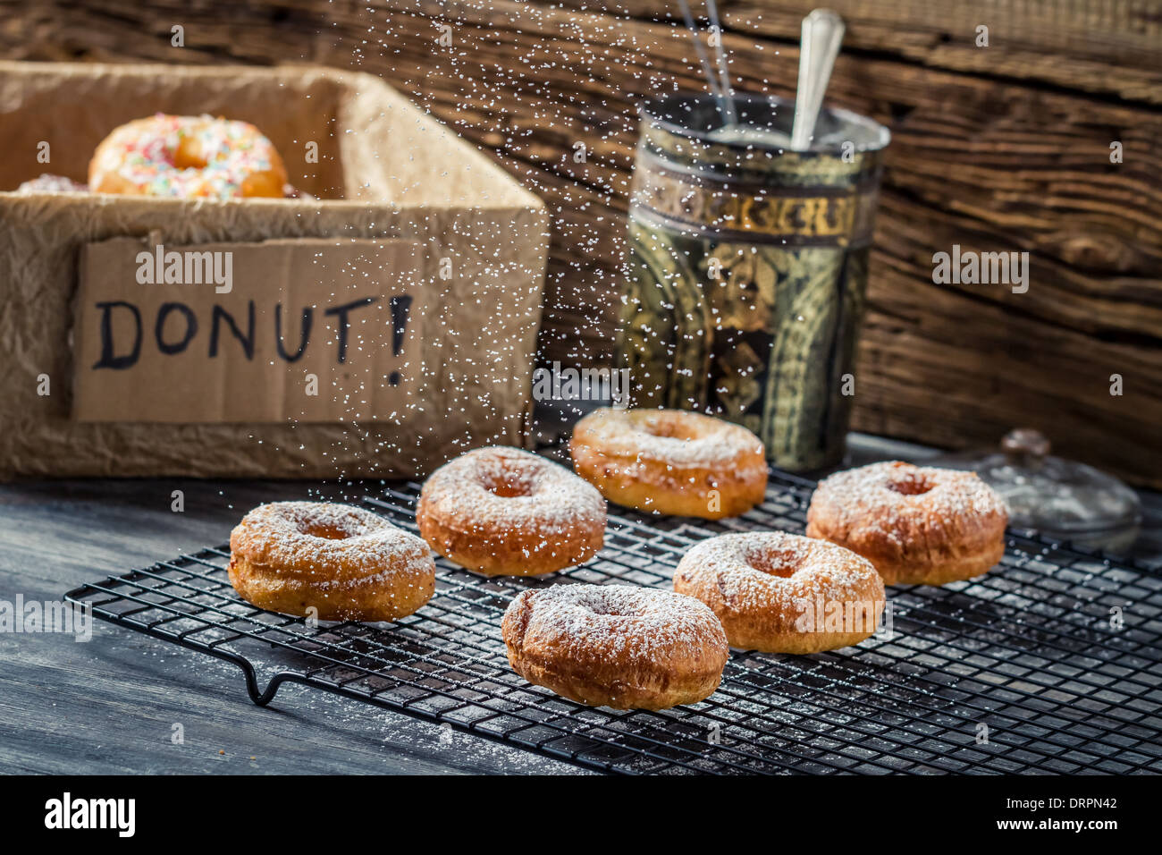 Icing sugar falling on fresh donuts Stock Photo - Alamy