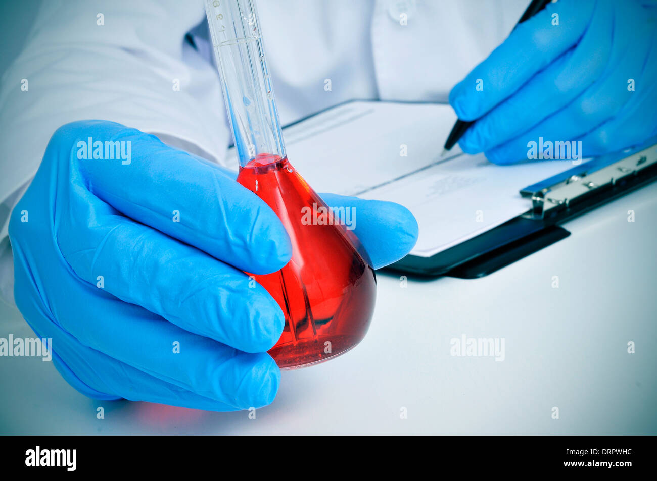 man in white coat with a volumetric flask with a red liquid in a ...