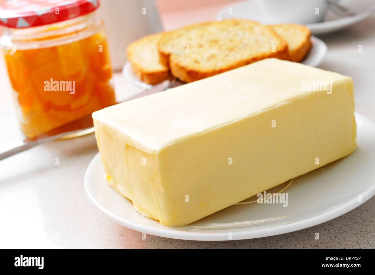 closeup of a plate with butter and pile of toast and a jam jar in the ...