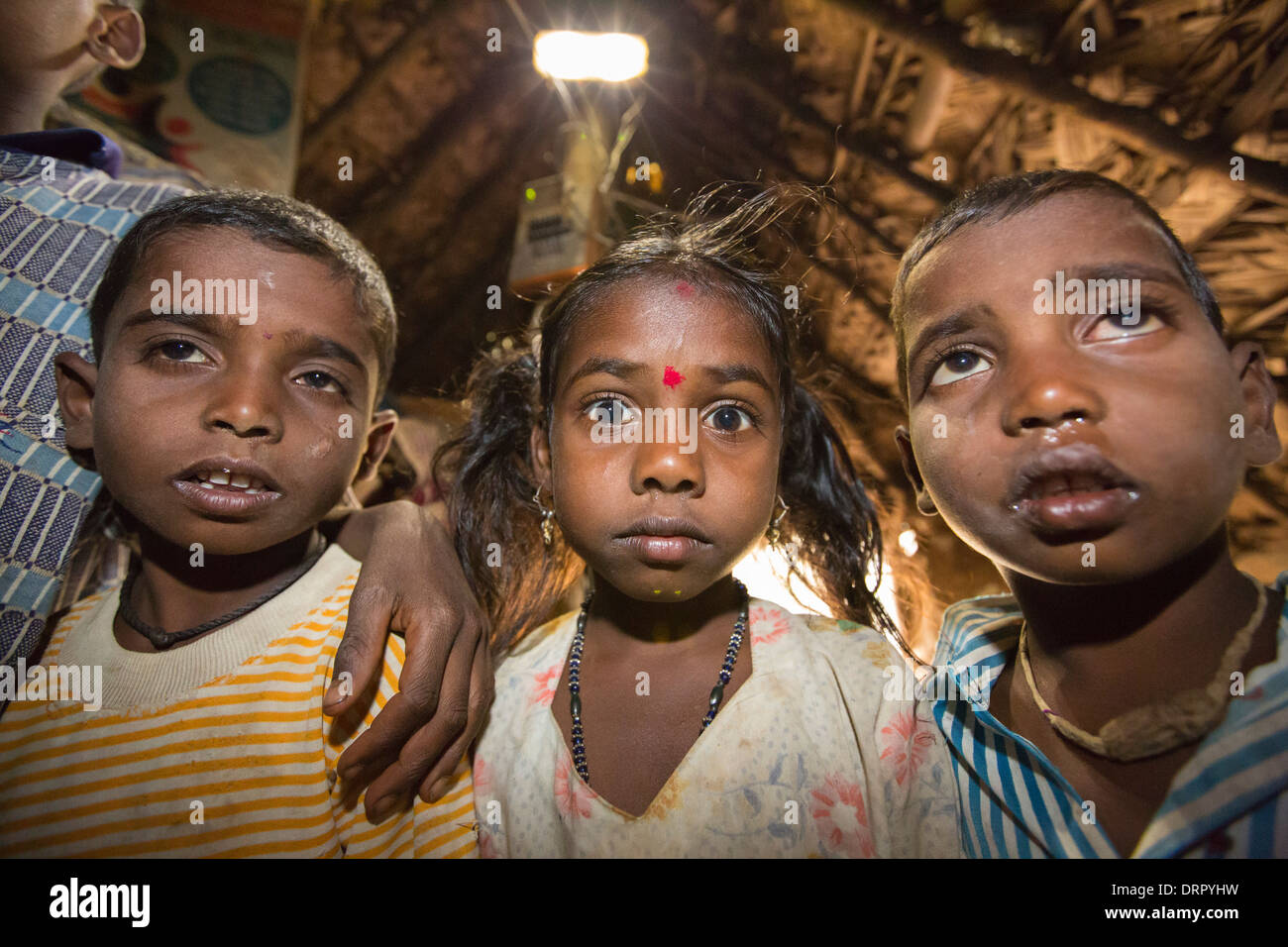 An untouchable family in their hut, illuminated by an electric light ...