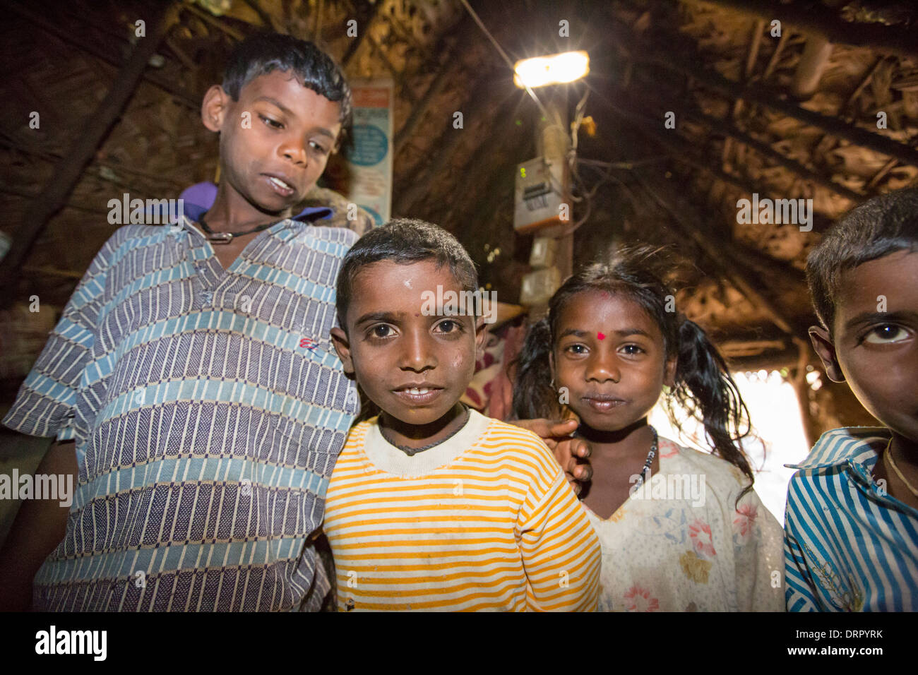 An untouchable family in their hut, illuminated by an electric light ...