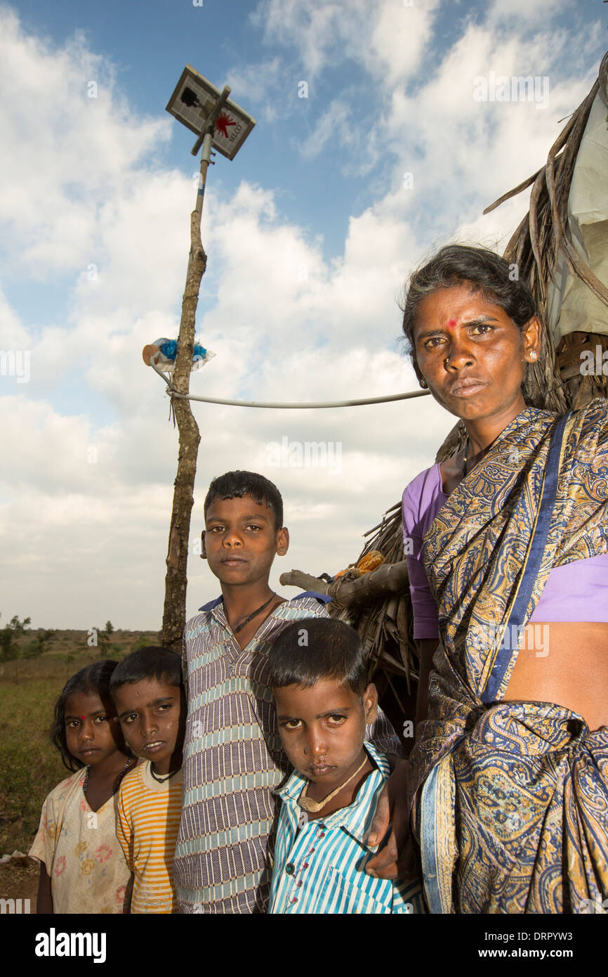 An untouchable family outside their hut, illuminated by an electric ...