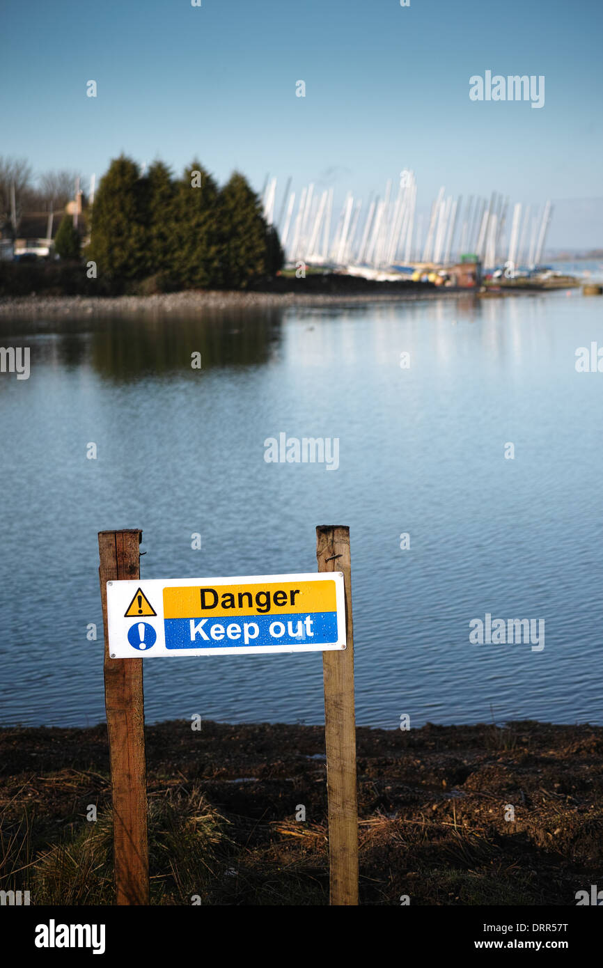 Danger keep out sign nailed to two posts at the edge of a lake Stock ...