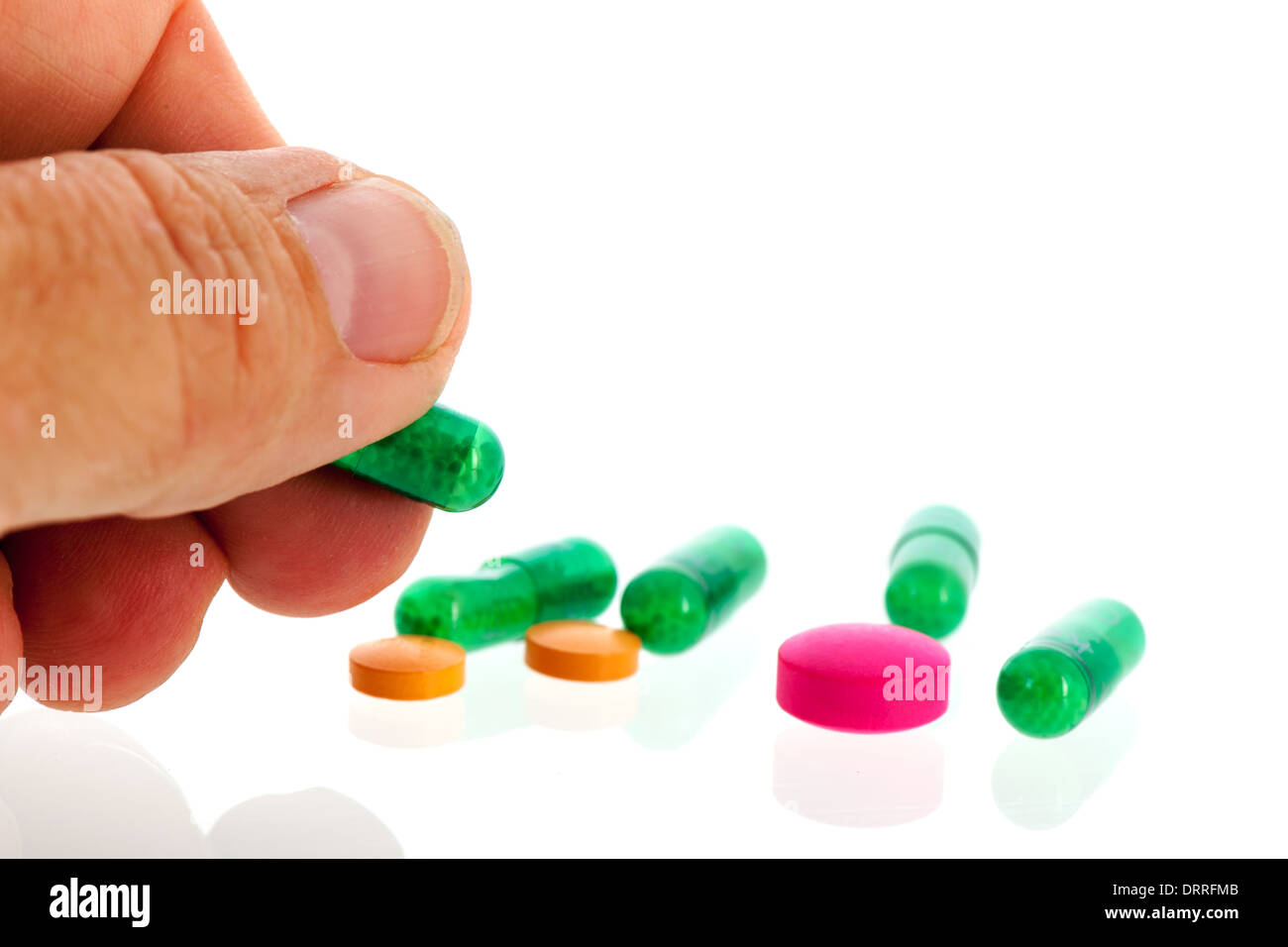Old hand with green medicine in capsules isolated over white background ...