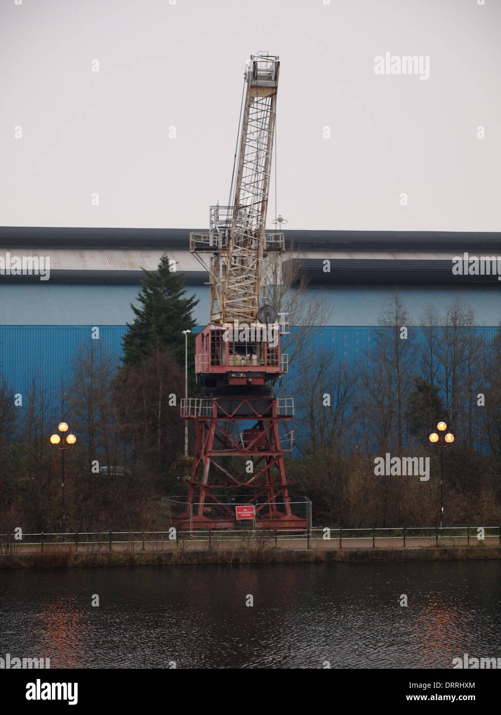 dock crane with industrial building in the background and water in the ...