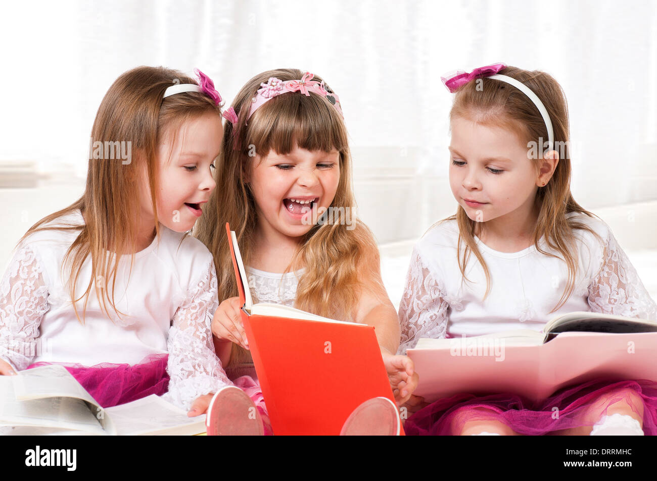 Girls reading book Stock Photo - Alamy