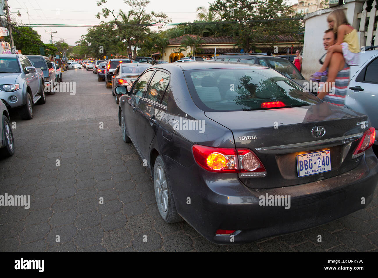 A daughter rides on her fathers shoulders navigating a traffic jam in ...
