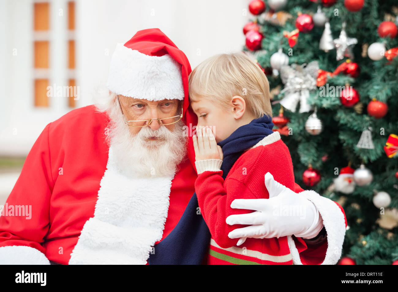 Boy Whispering In Santa Claus's Ear Stock Photo - Alamy