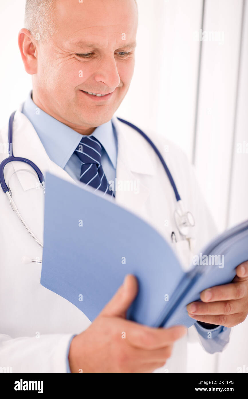 Mature doctor male look down in document Stock Photo - Alamy