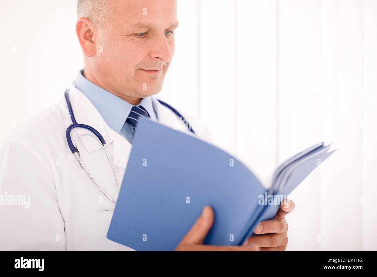 Mature doctor male look down in document Stock Photo - Alamy