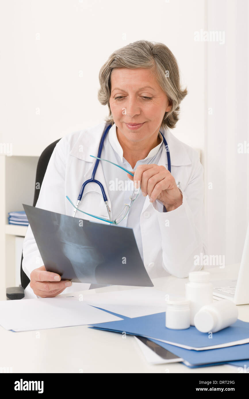 Senior doctor female sit behind office desk Stock Photo - Alamy