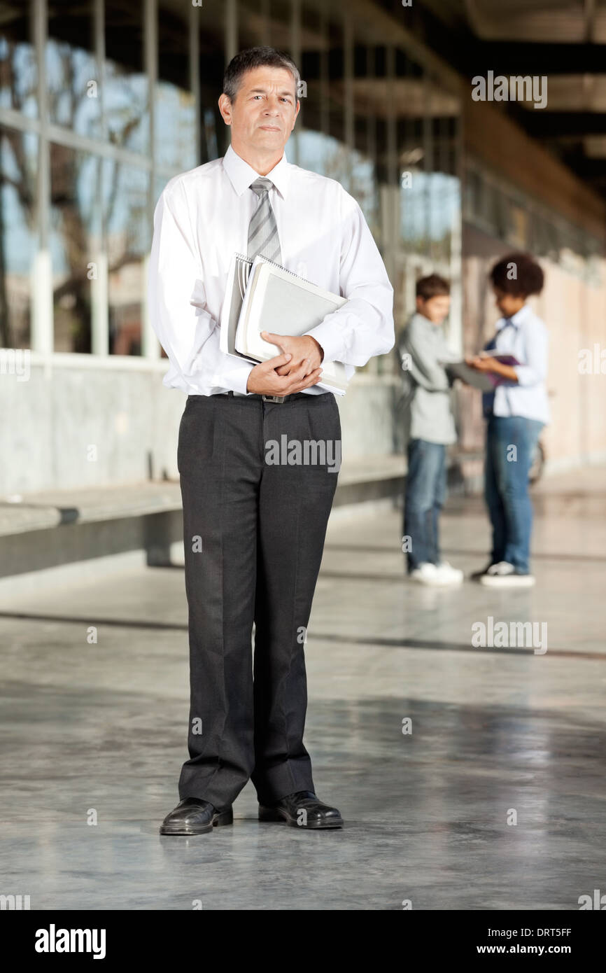 Mature Professor With Books Standing On College Campus Stock Photo - Alamy