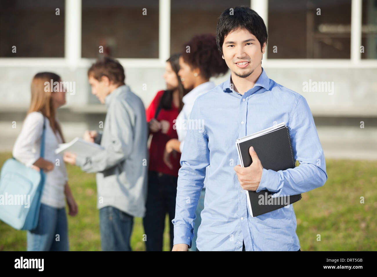 Man Holding Book With Students In Background On Campus Stock Photo - Alamy