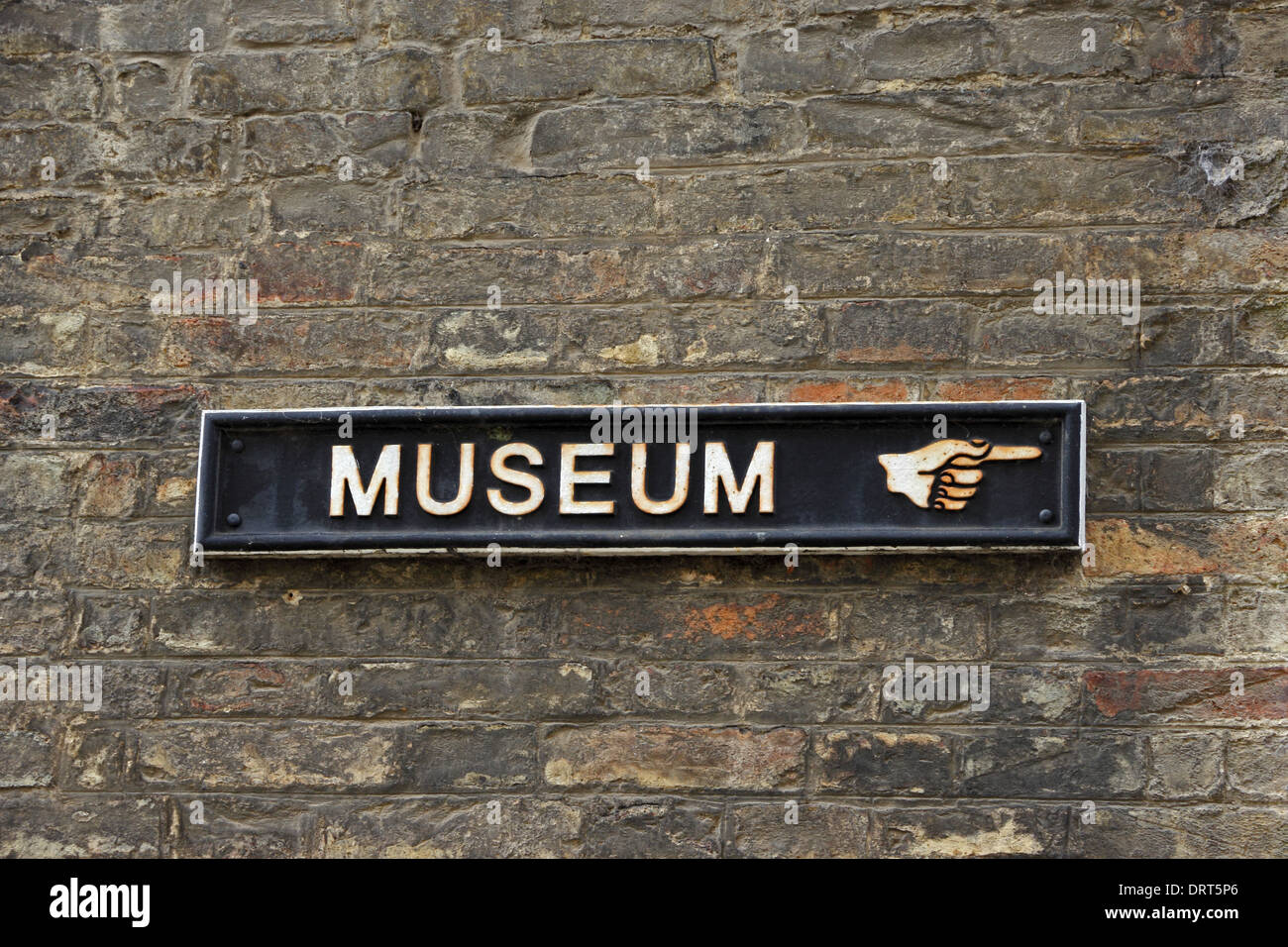 Sign pointing way to Museum on stone wall Stock Photo - Alamy