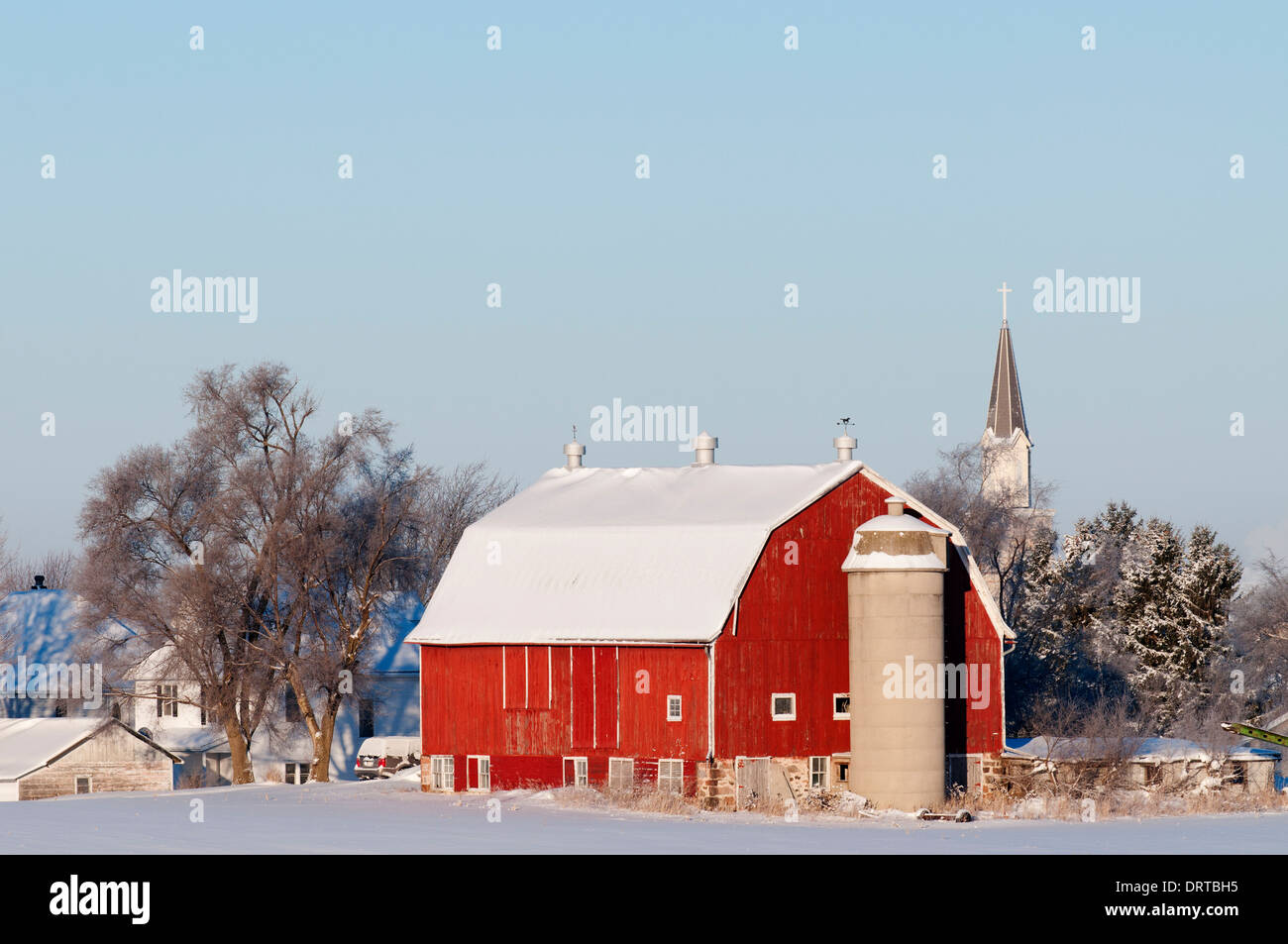 Traditional red barn on the outskirts of a rural village with church ...